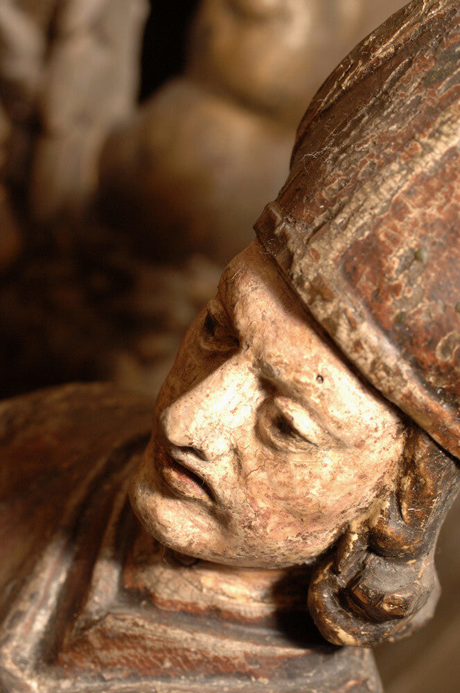 Close view of the head of a carved wooden figure of a bishop, part of ...