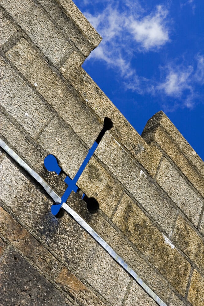 A decorative arrow slit on the battlemented roofline of Castle Drogo ...